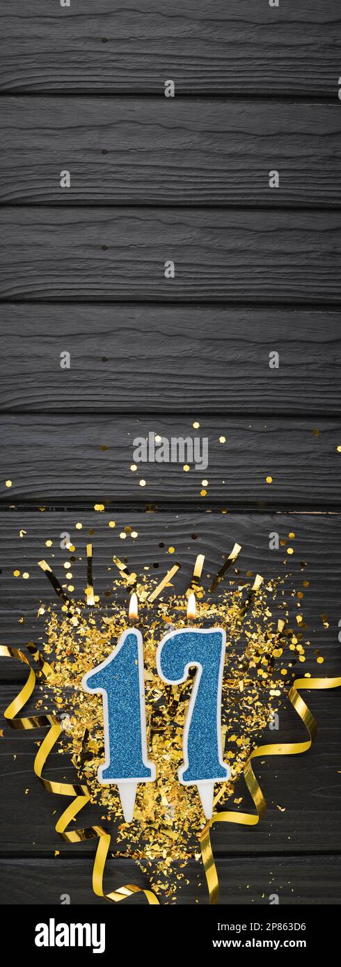 Number 17 blue celebration candle and gold confetti on dark wooden ...