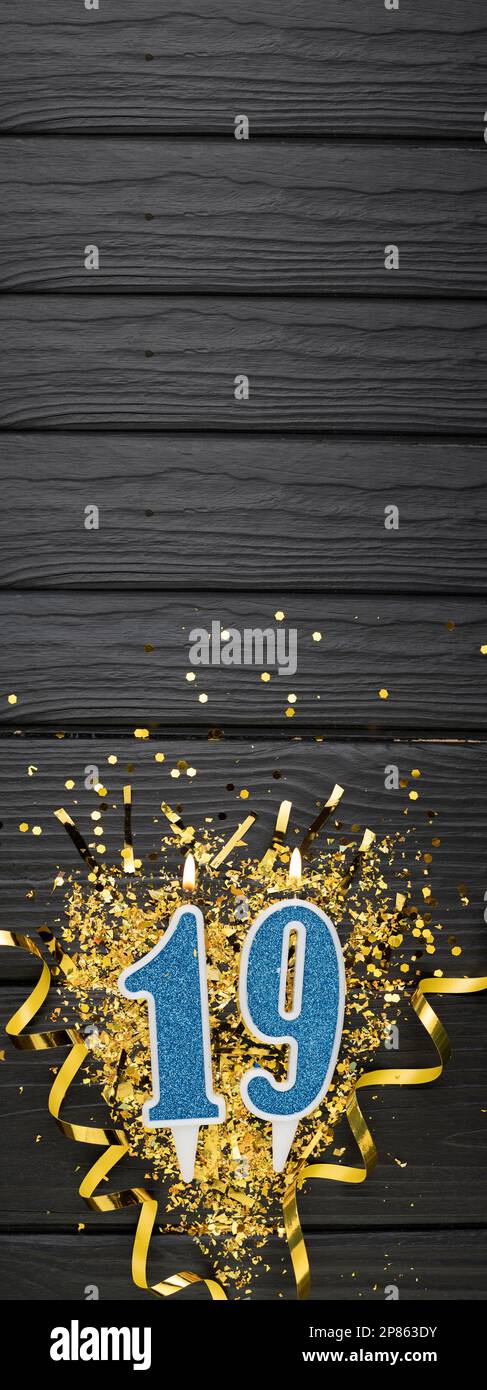 Number 19 blue celebration candle and gold confetti on dark wooden ...