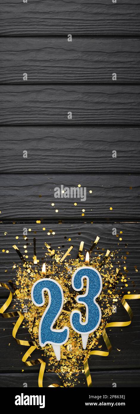 Number 23 blue celebration candle and gold confetti on dark wooden ...