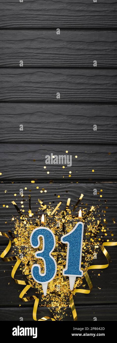 Number 31 blue celebration candle and gold confetti on dark wooden ...