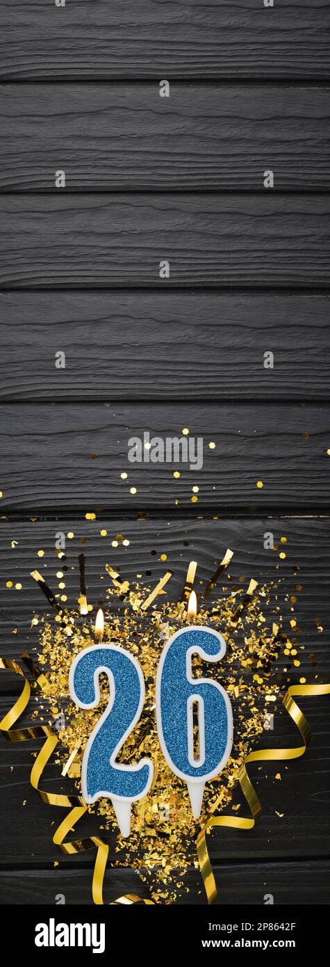 Number 26 blue celebration candle and gold confetti on dark wooden ...