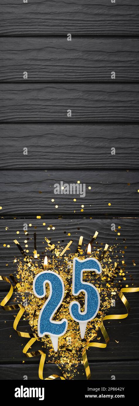 Number 25 blue celebration candle and gold confetti on dark wooden ...