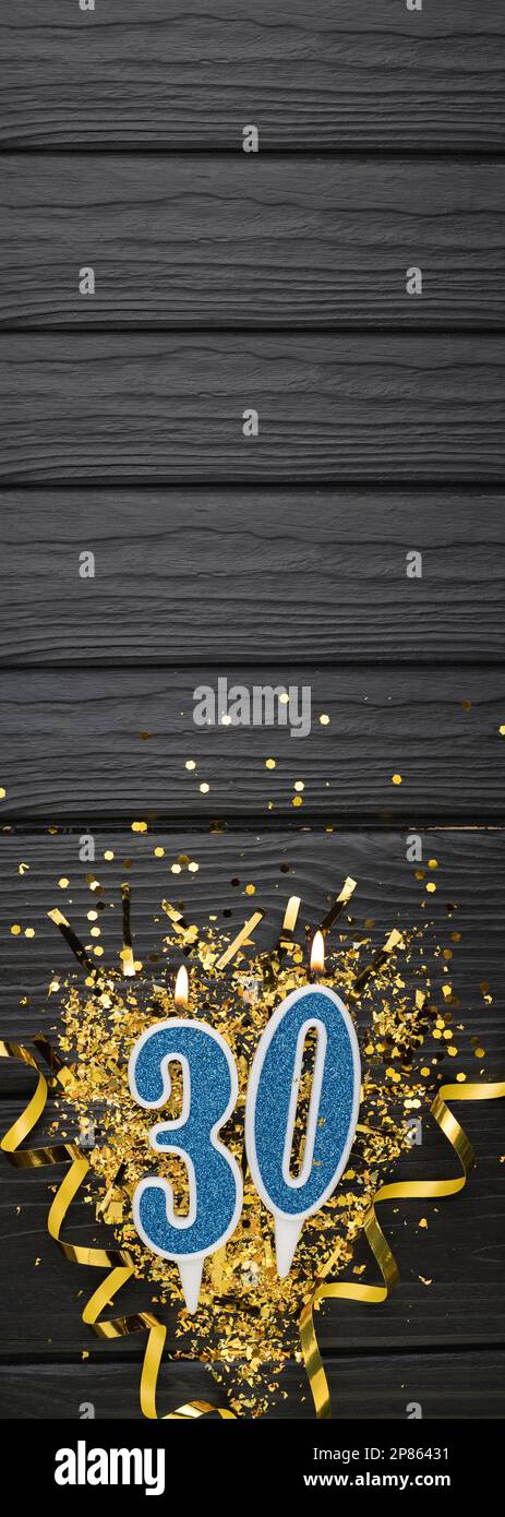 Number 30 blue celebration candle and gold confetti on dark wooden ...