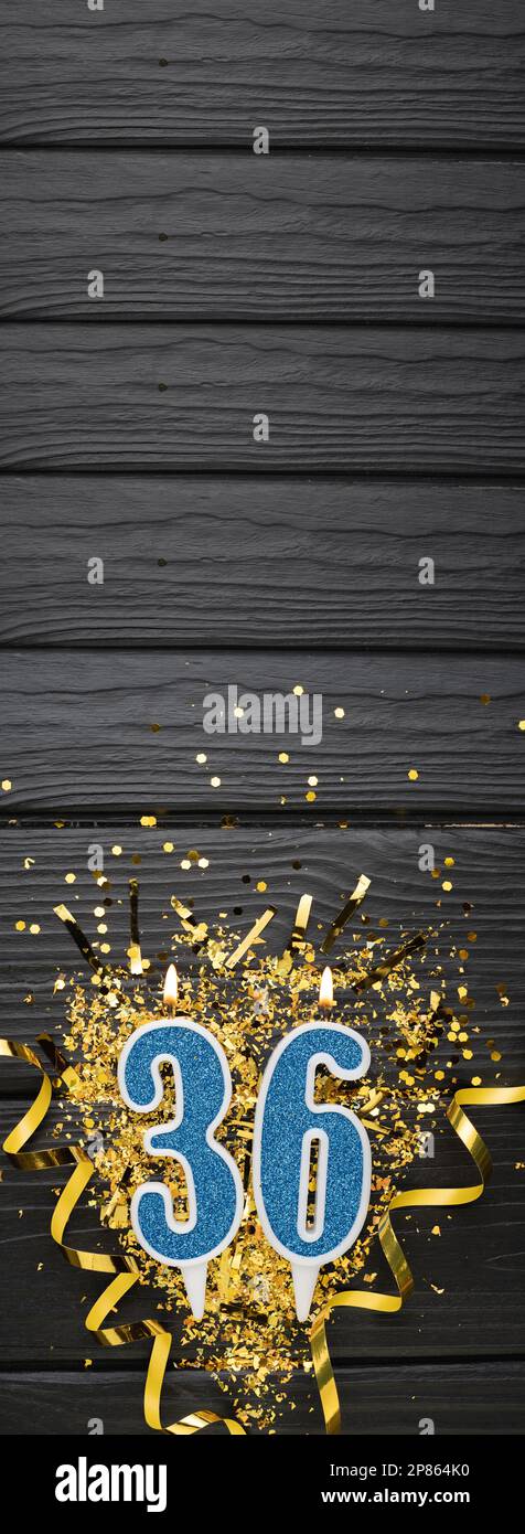 Number 36 blue celebration candle and gold confetti on dark wooden ...