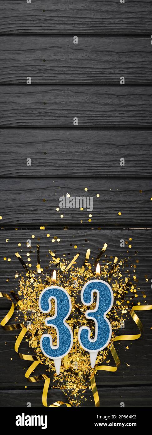 Number 33 Blue Celebration Candle And Gold Confetti On Dark Wooden