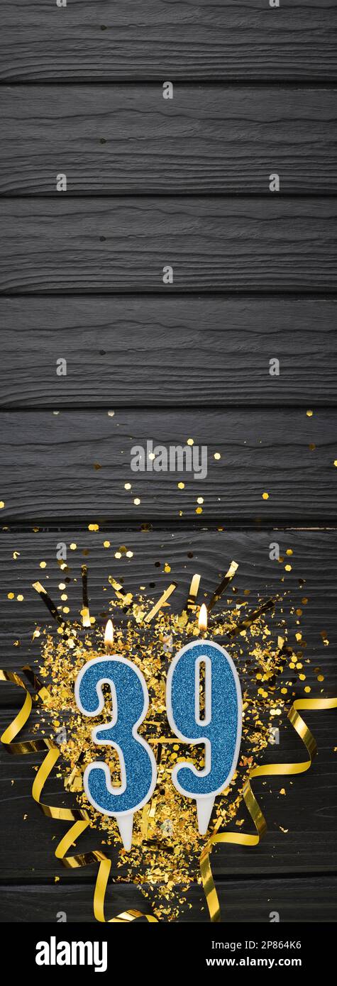 Number 39 blue celebration candle and gold confetti on dark wooden ...