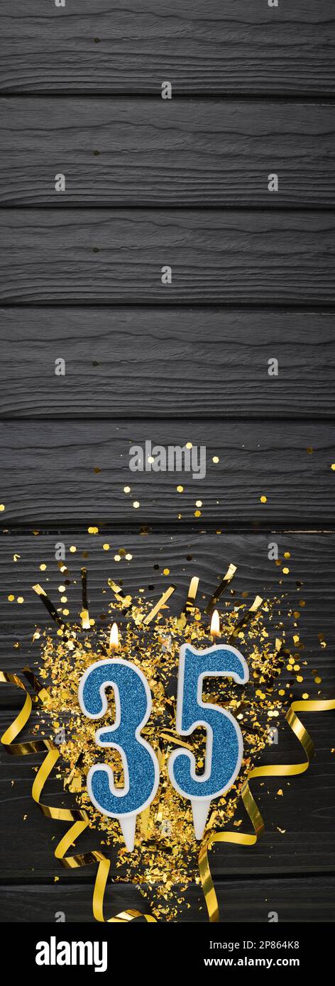 Number 35 blue celebration candle and gold confetti on dark wooden ...