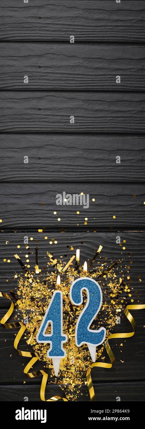 Number 42 blue celebration candle and gold confetti on dark wooden ...