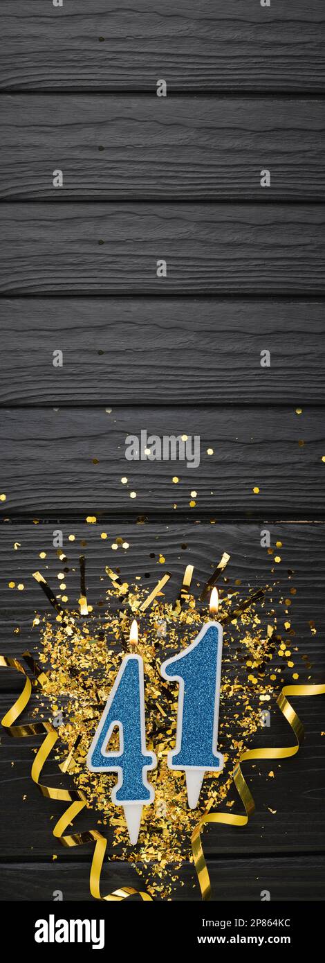 Number 41 blue celebration candle and gold confetti on dark wooden ...