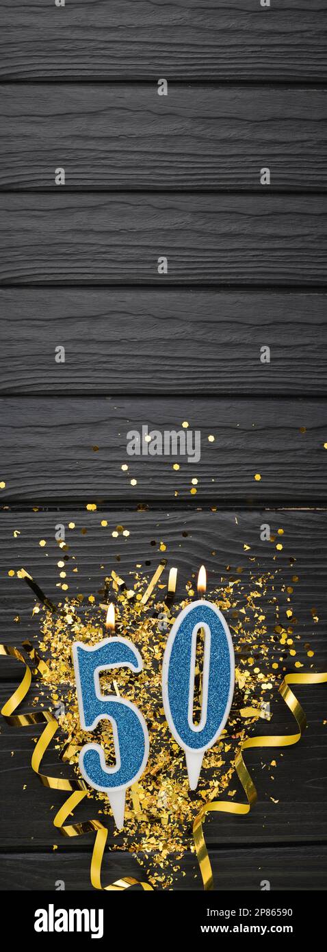 Number 50 blue celebration candle and gold confetti on dark wooden ...