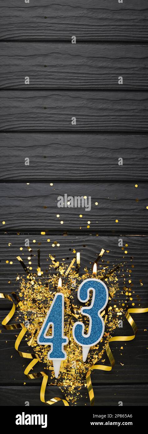 Number 43 blue celebration candle and gold confetti on dark wooden ...
