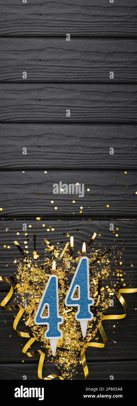Number 44 blue celebration candle and gold confetti on dark wooden ...