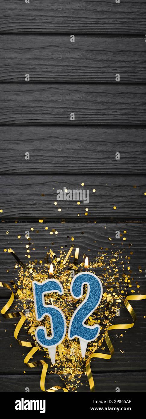 Number 52 blue celebration candle and gold confetti on dark wooden ...