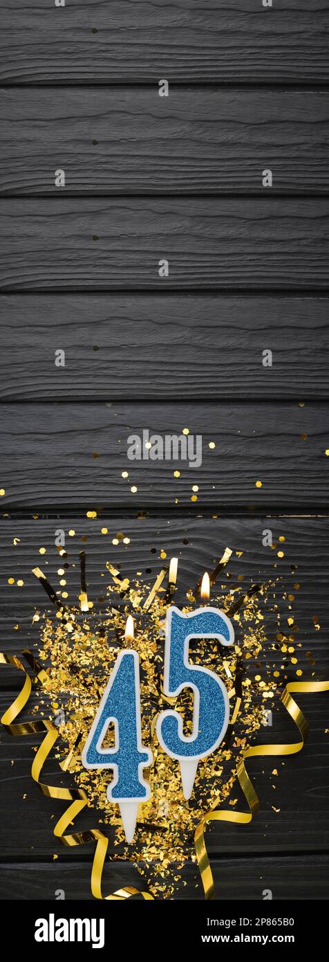 Number 45 blue celebration candle and gold confetti on dark wooden ...
