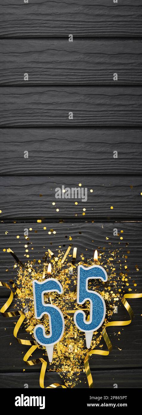 Number 55 blue celebration candle and gold confetti on dark wooden ...