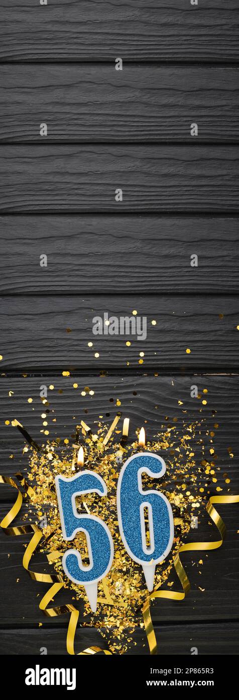Number 56 blue celebration candle and gold confetti on dark wooden ...