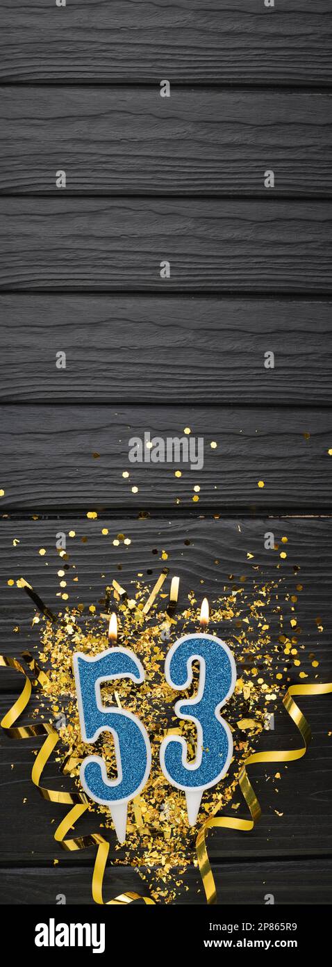 Number 53 blue celebration candle and gold confetti on dark wooden ...