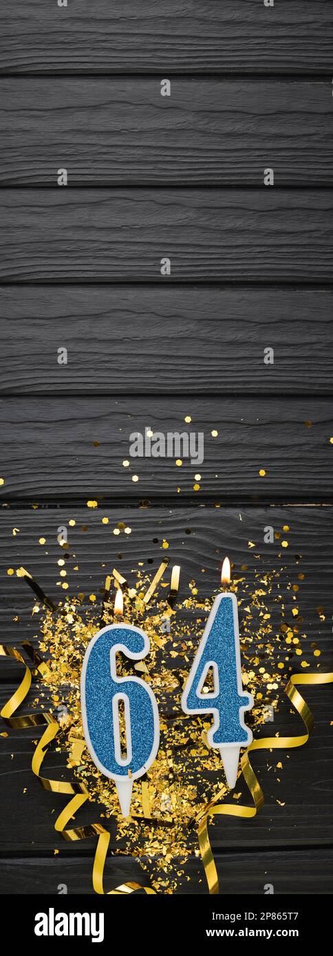 Number 64 blue celebration candle and gold confetti on dark wooden ...