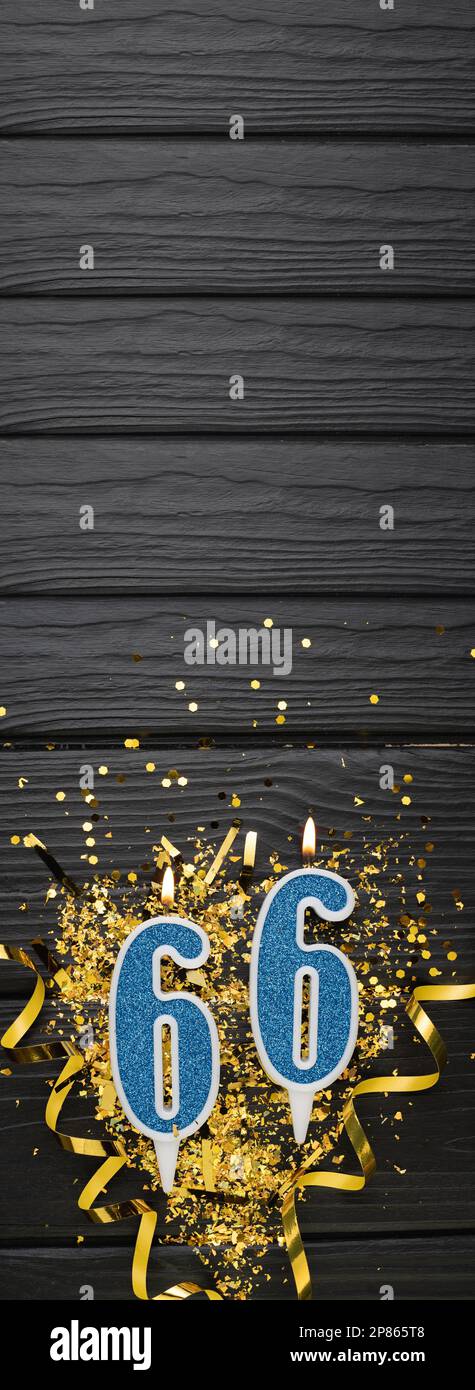 Number 66 blue celebration candle and gold confetti on dark wooden ...