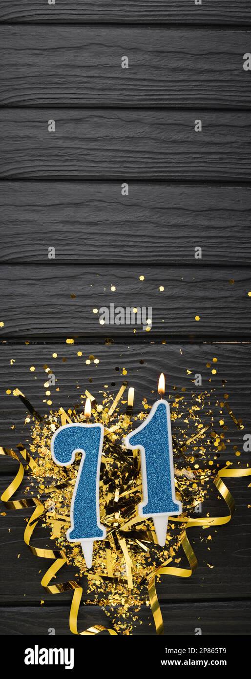 Number 71 blue celebration candle and gold confetti on dark wooden ...