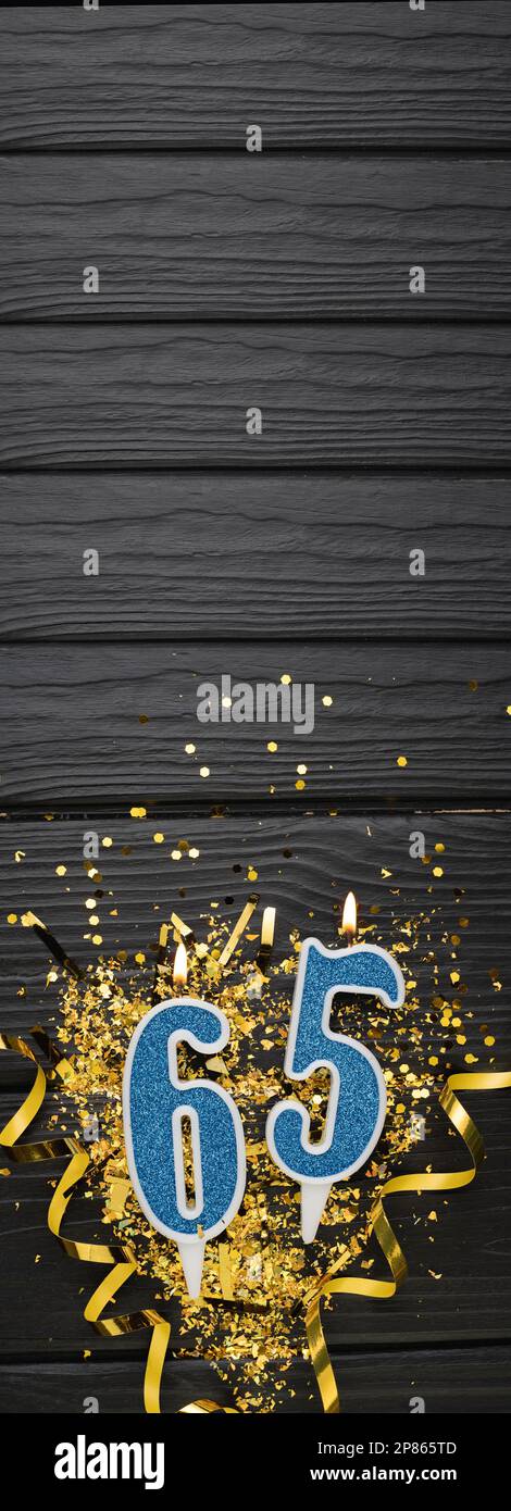 Number 65 Blue Celebration Candle And Gold Confetti On Dark Wooden