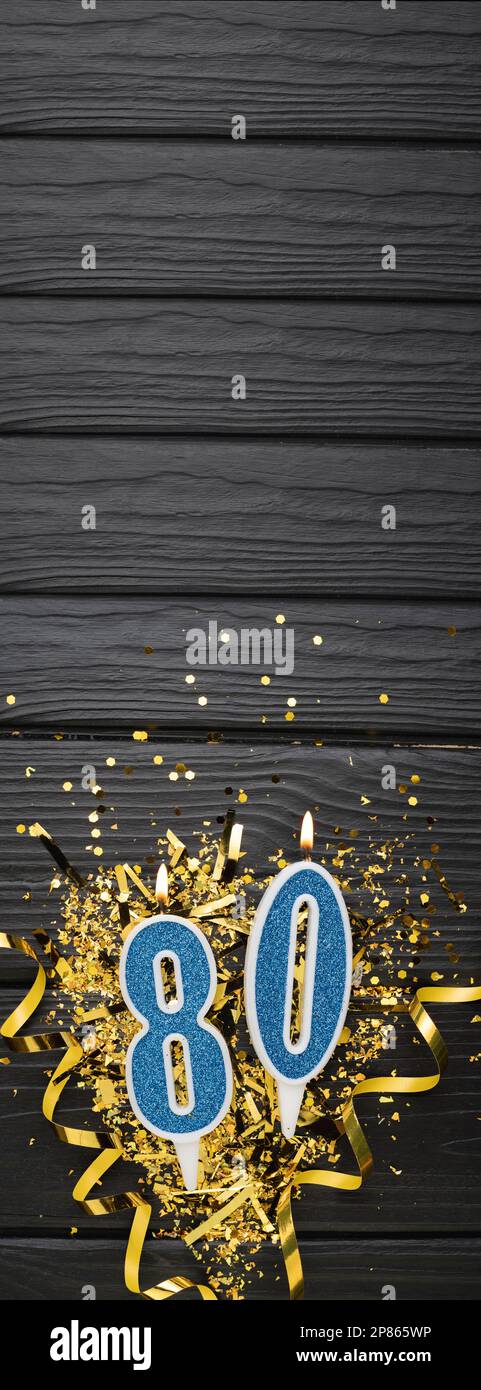 Number 80 blue celebration candle and gold confetti on dark wooden ...