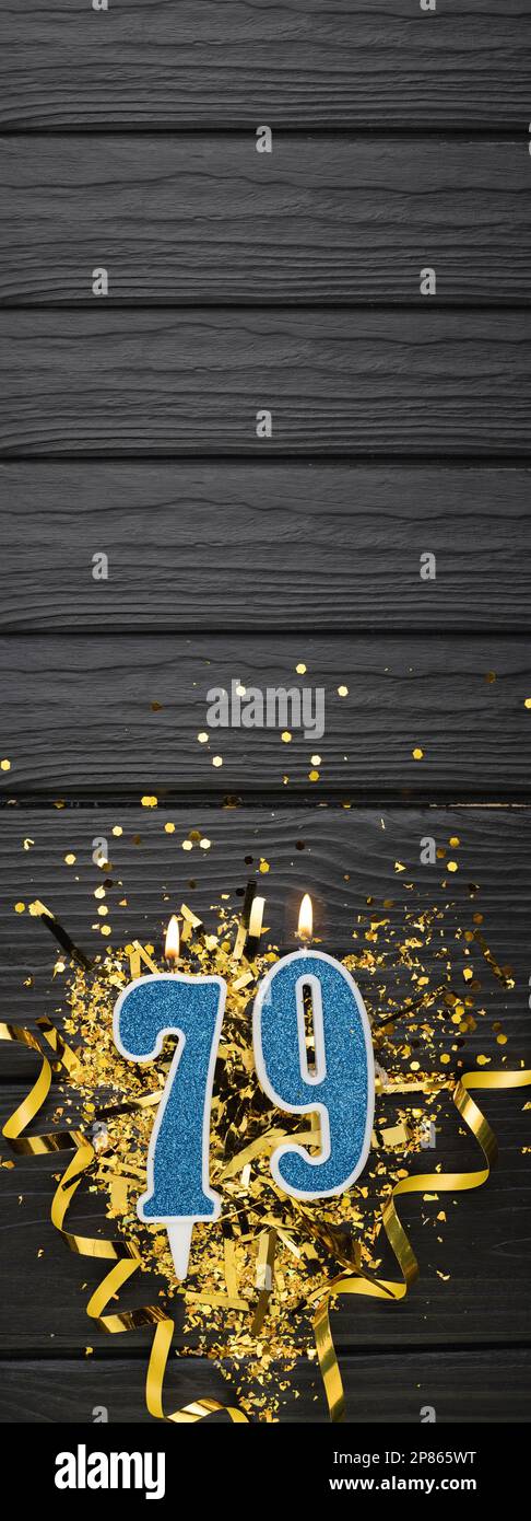 Number 79 blue celebration candle and gold confetti on dark wooden ...