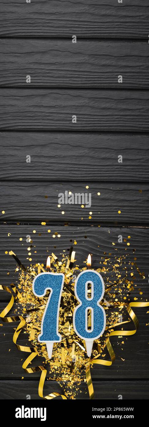 Number 78 blue celebration candle and gold confetti on dark wooden ...