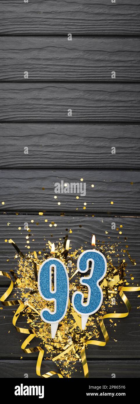 Number 93 blue celebration candle and gold confetti on dark wooden ...