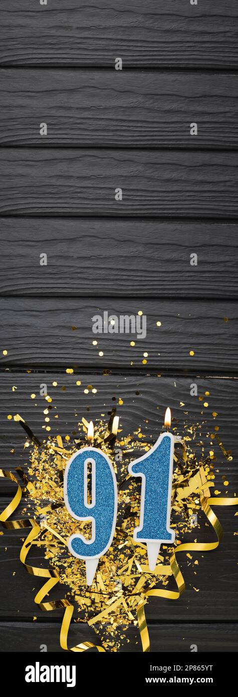 Number 91 blue celebration candle and gold confetti on dark wooden ...
