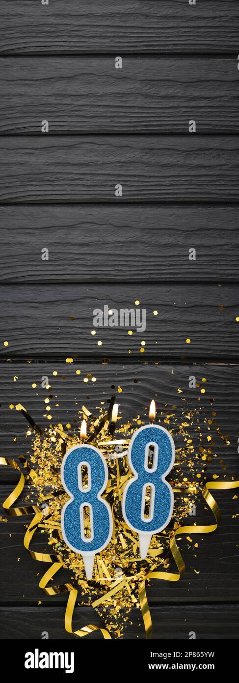 Number 88 blue celebration candle and gold confetti on dark wooden ...