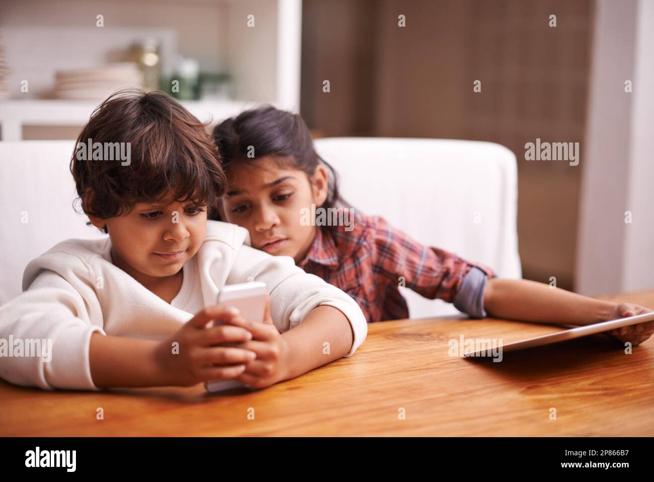 Siblings gone digital. two siblings playing with their digital devices ...