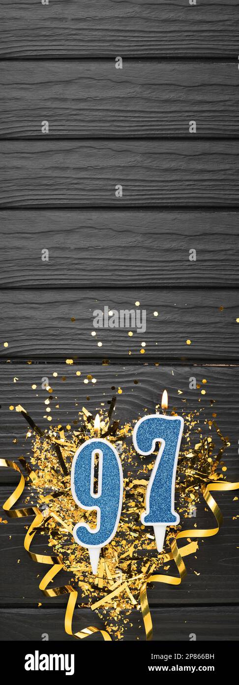 Number 97 blue celebration candle and gold confetti on dark wooden ...