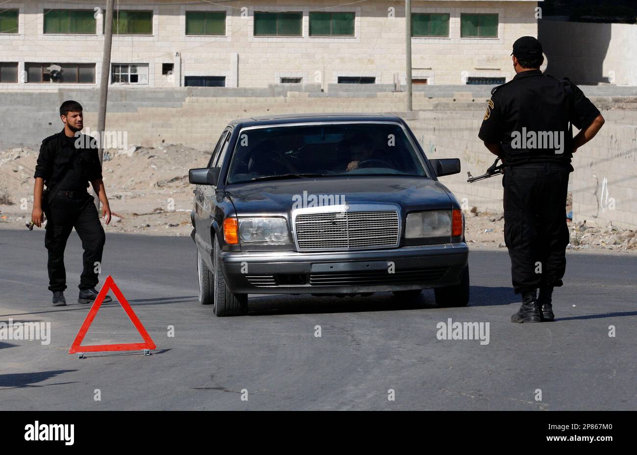 Hamas police officers stop a car at a makeshift roadblock on the ...