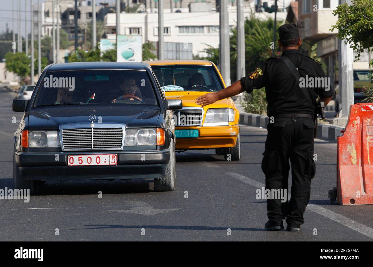 Hamas police officers stop a car at a makeshift roadblock on the ...