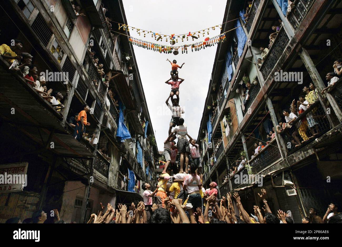 Devotees form a human pyramid to reach a vessel containing butter ...