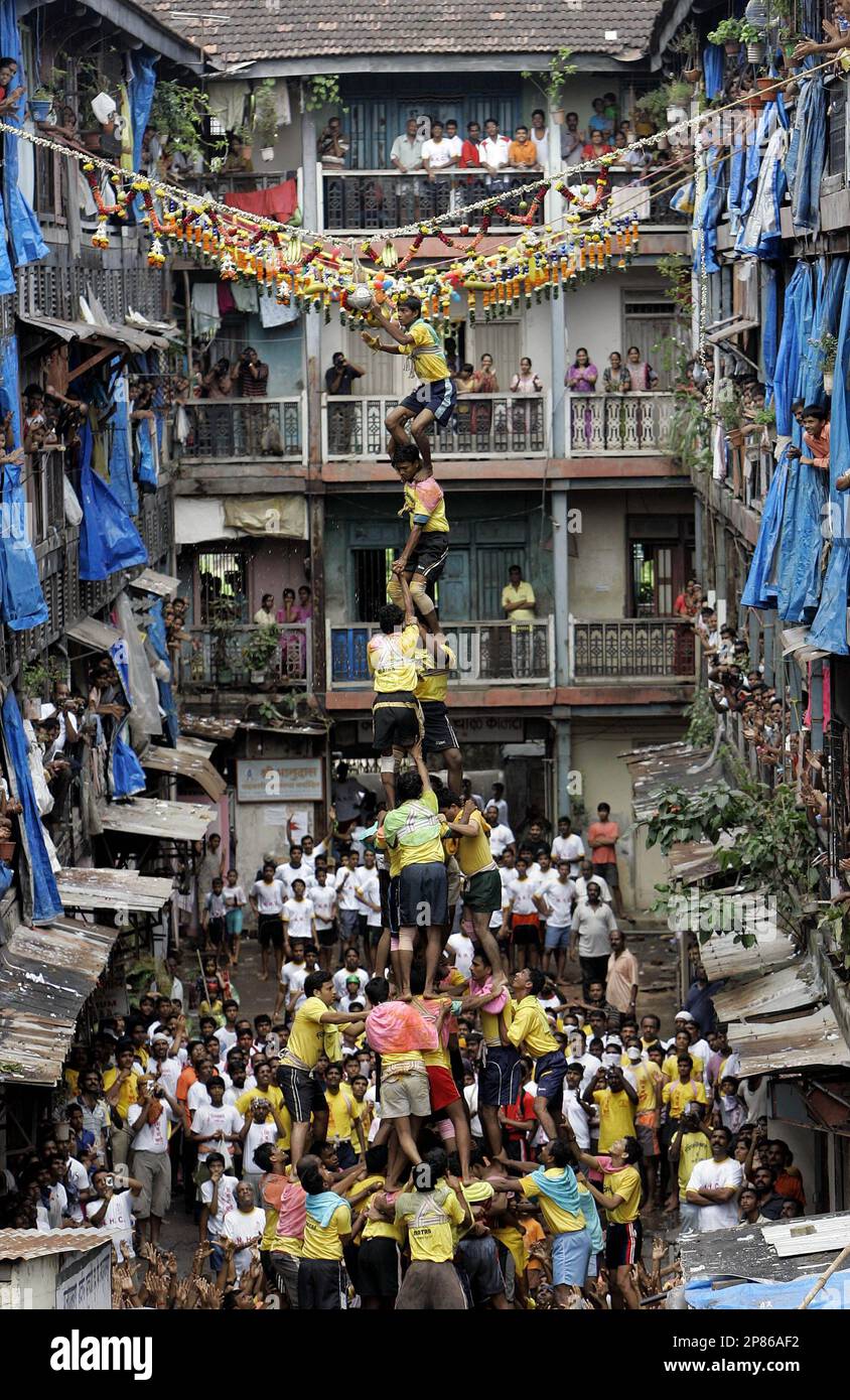 Devotees form a human pyramid to reach a vessel containing butter ...