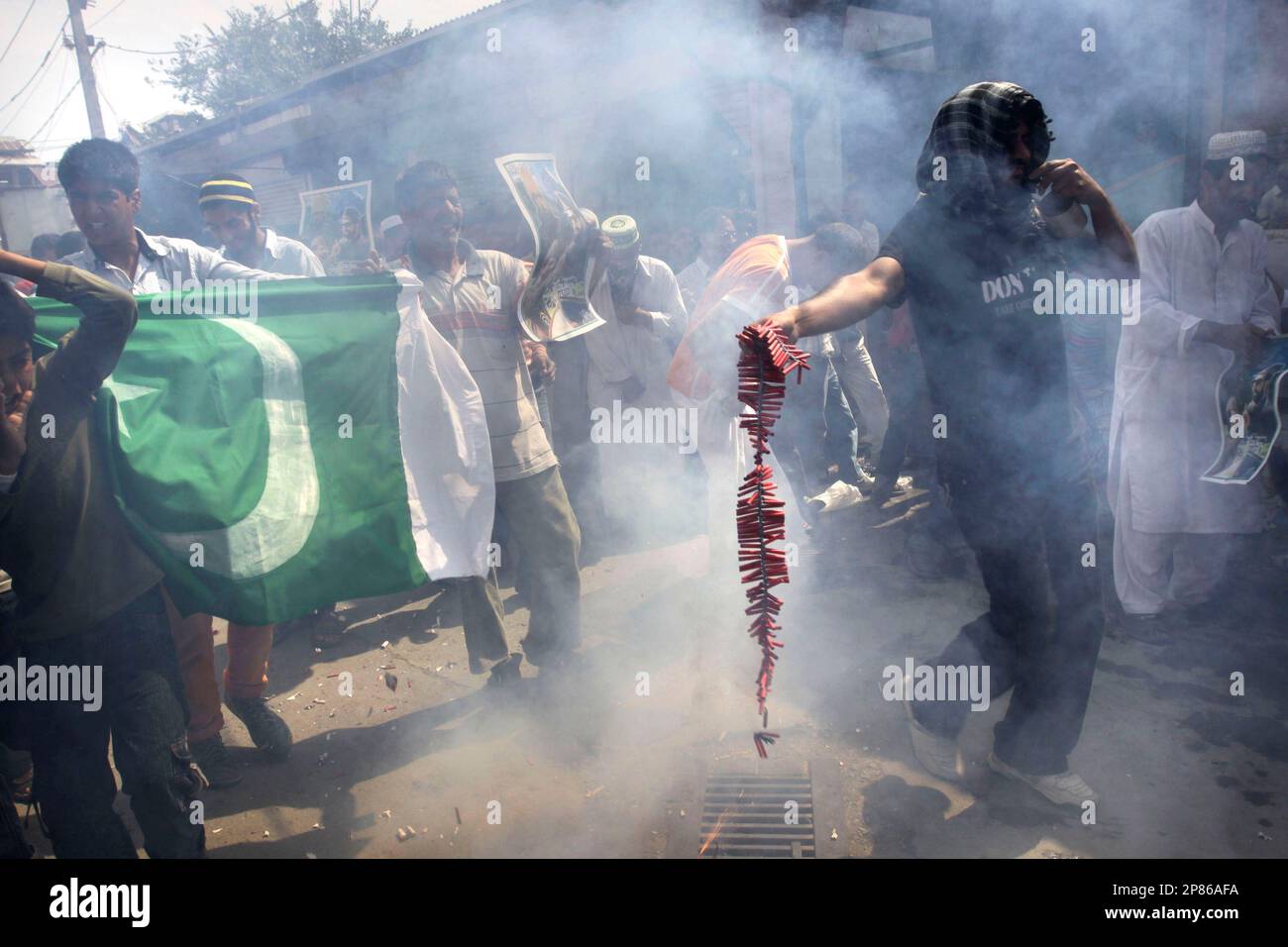 Kashmiri people burn firecrackers and hold a flag of Pakistan as they ...