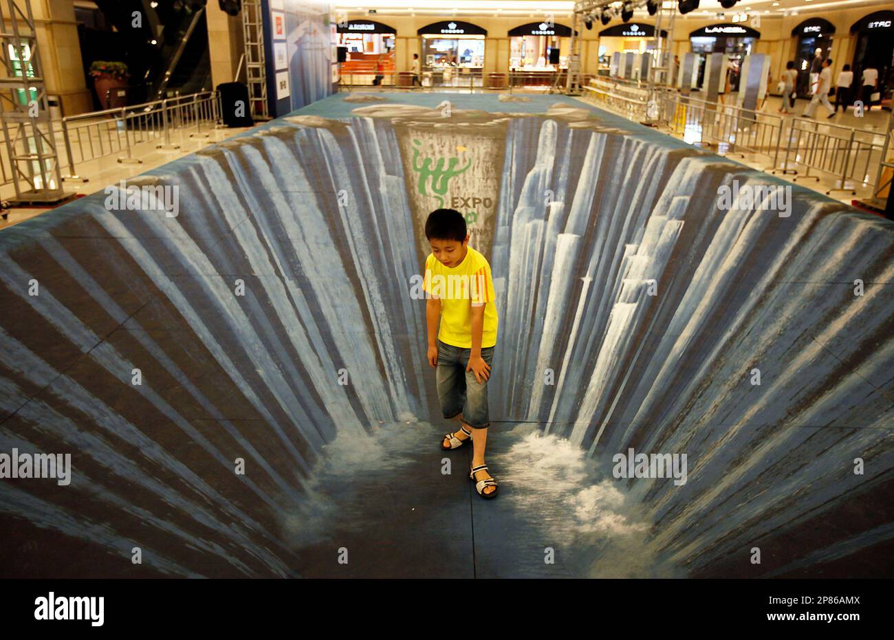 A young visitor stands on a three dimensional visual effect painting at ...