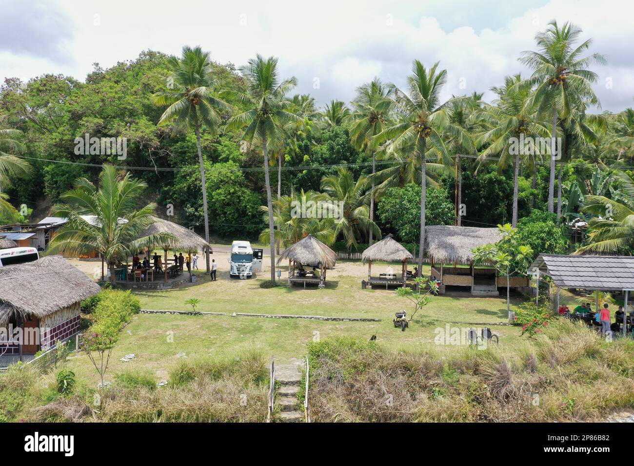 Panorama drone shot of a green space with thatched huts enclosed by ...