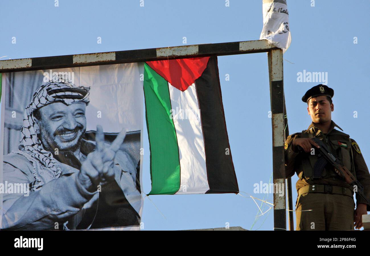 A Palestinian security officer stands guard next to a banner of Yasser ...