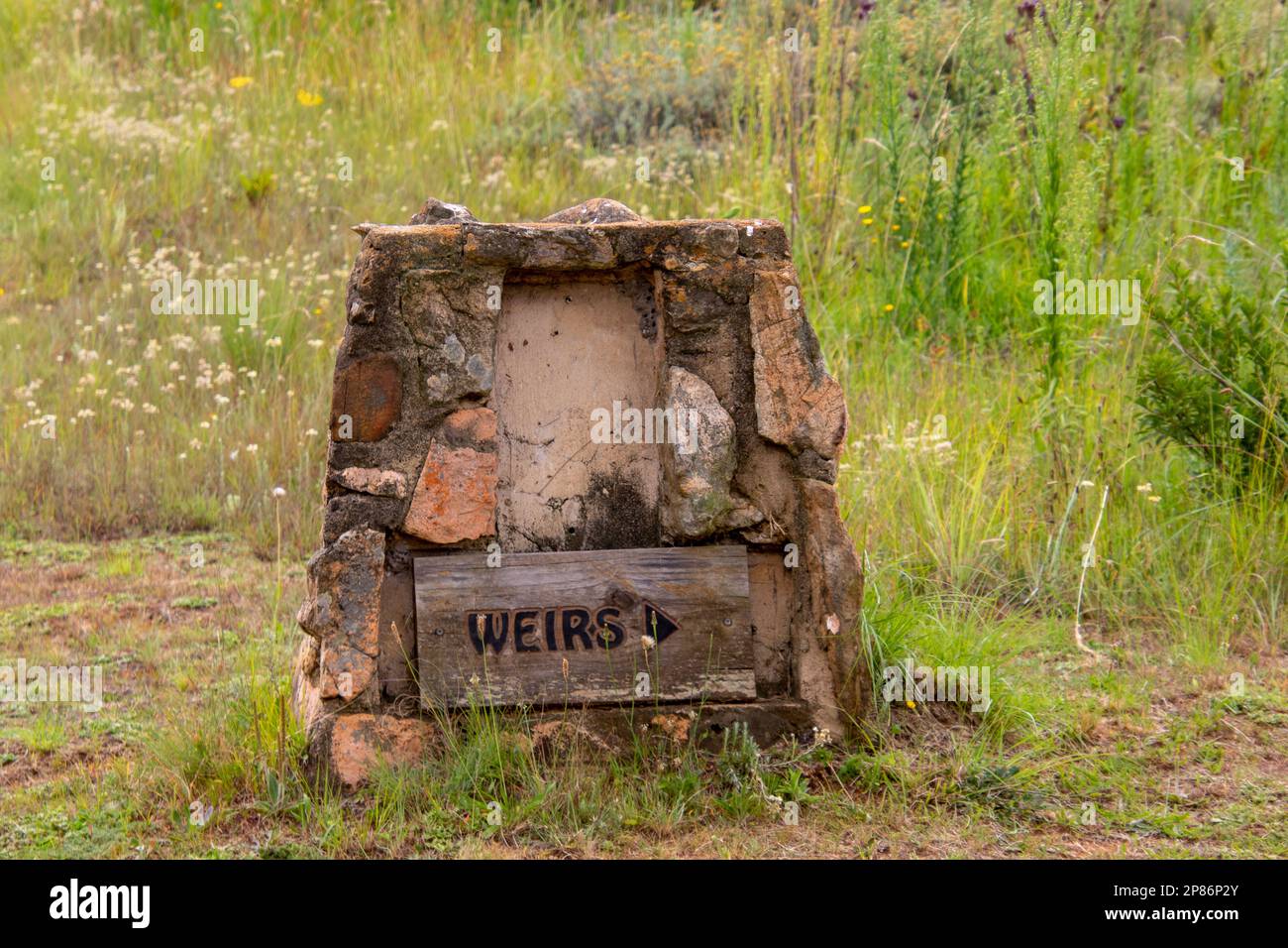 Weathered sign next to a grassy path indicating the direction to the ...