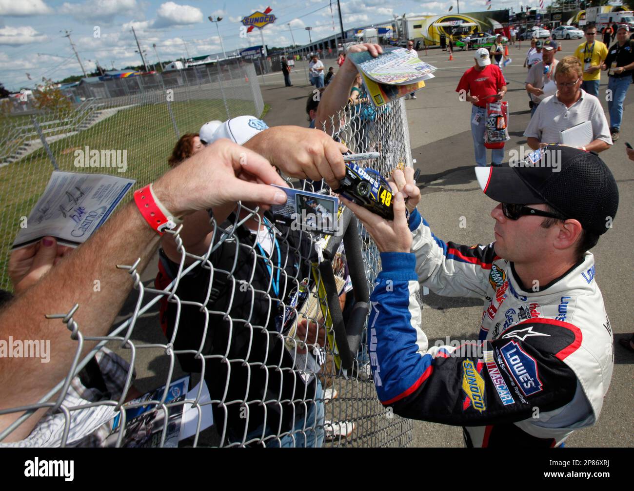 NASCAR driver Jimmie Johnson, right, signs autographs after winning the ...