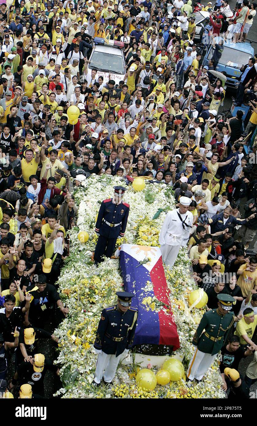 Filipinos crowd a street to pay their last respects to the late former ...