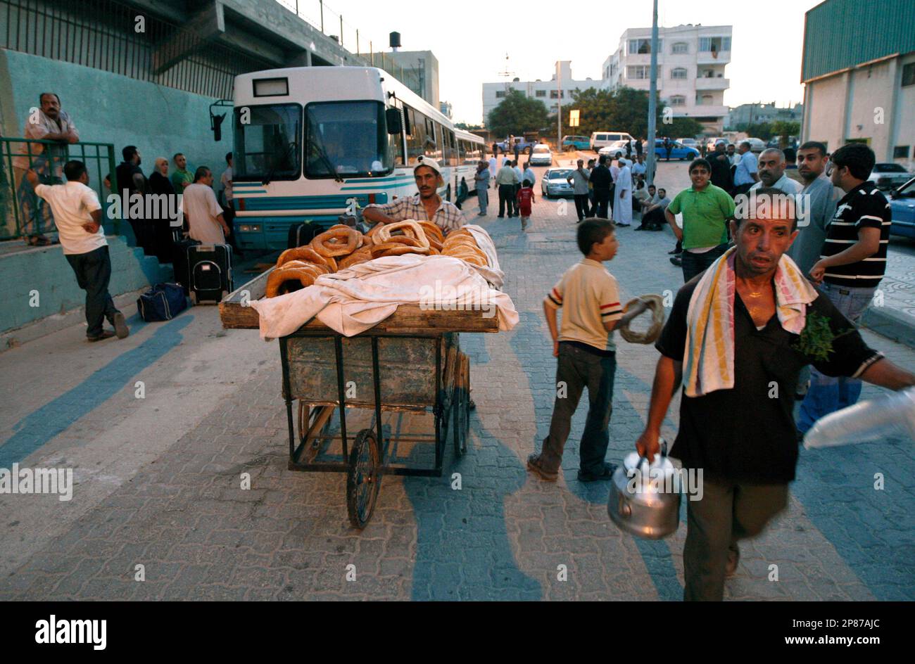 Palestinian vendors serve customers waiting to leave on a bus from Gaza ...