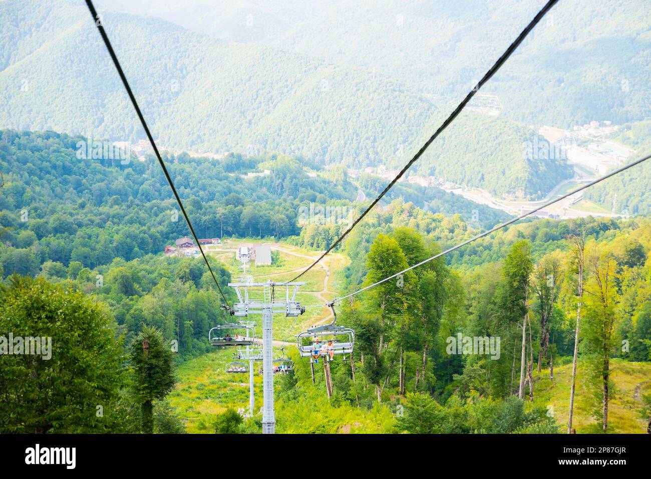 Open cable car line with people in mountains and forest on summer ...