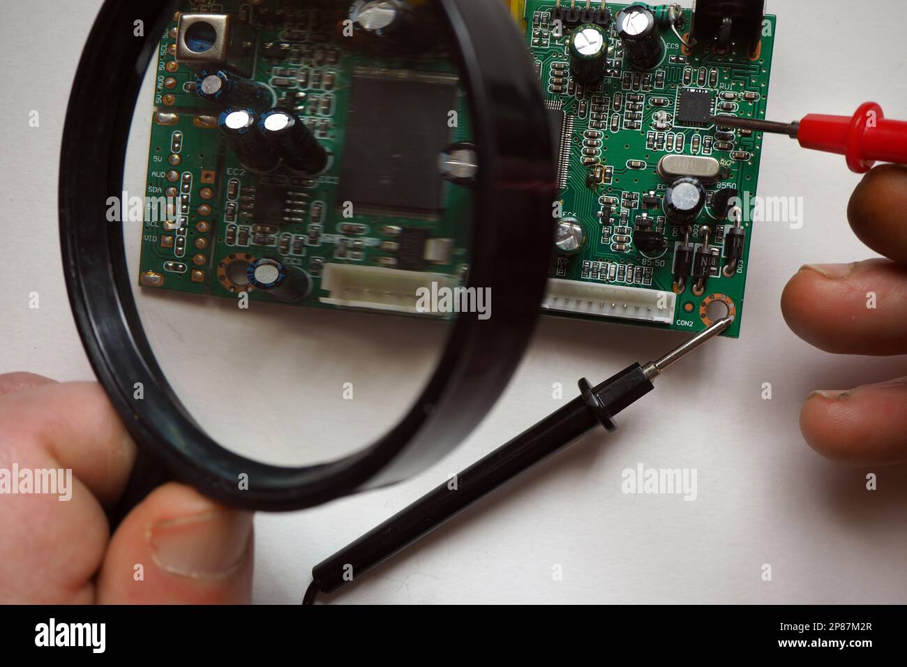 Technician working on microchip board with magnifying glass. Repair of ...
