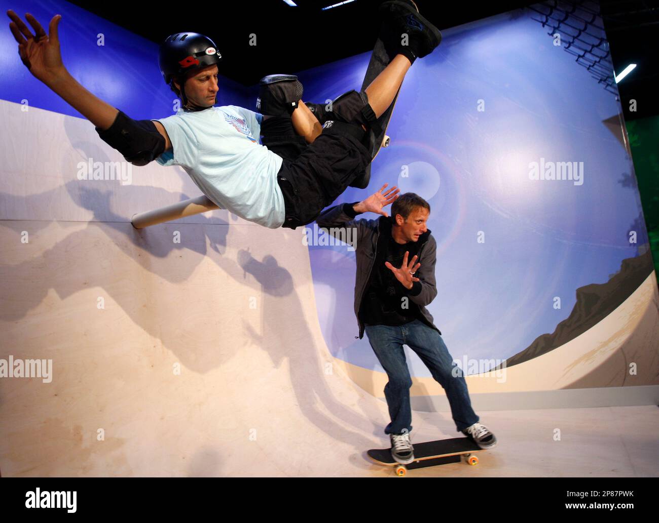 Professional skateboarder Tony Hawk stands on a skateboard next to his ...