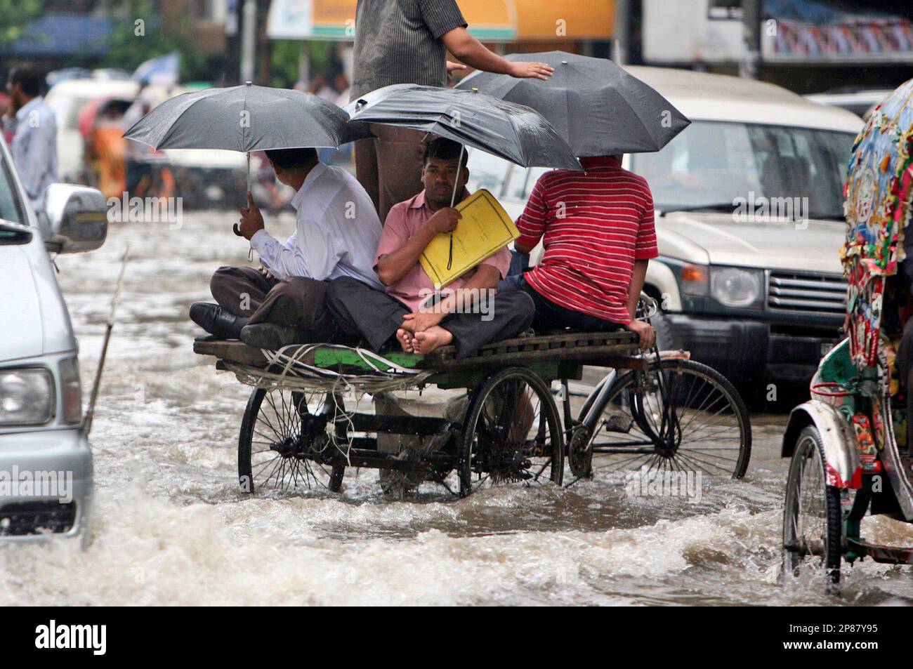 Bangladeshi commuters hold umbrellas to shield themselves from the rain, as they are transported ...