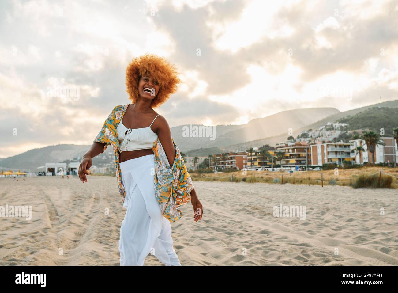 Happy woman with afro hairstyle walking on the beach Stock Photo - Alamy